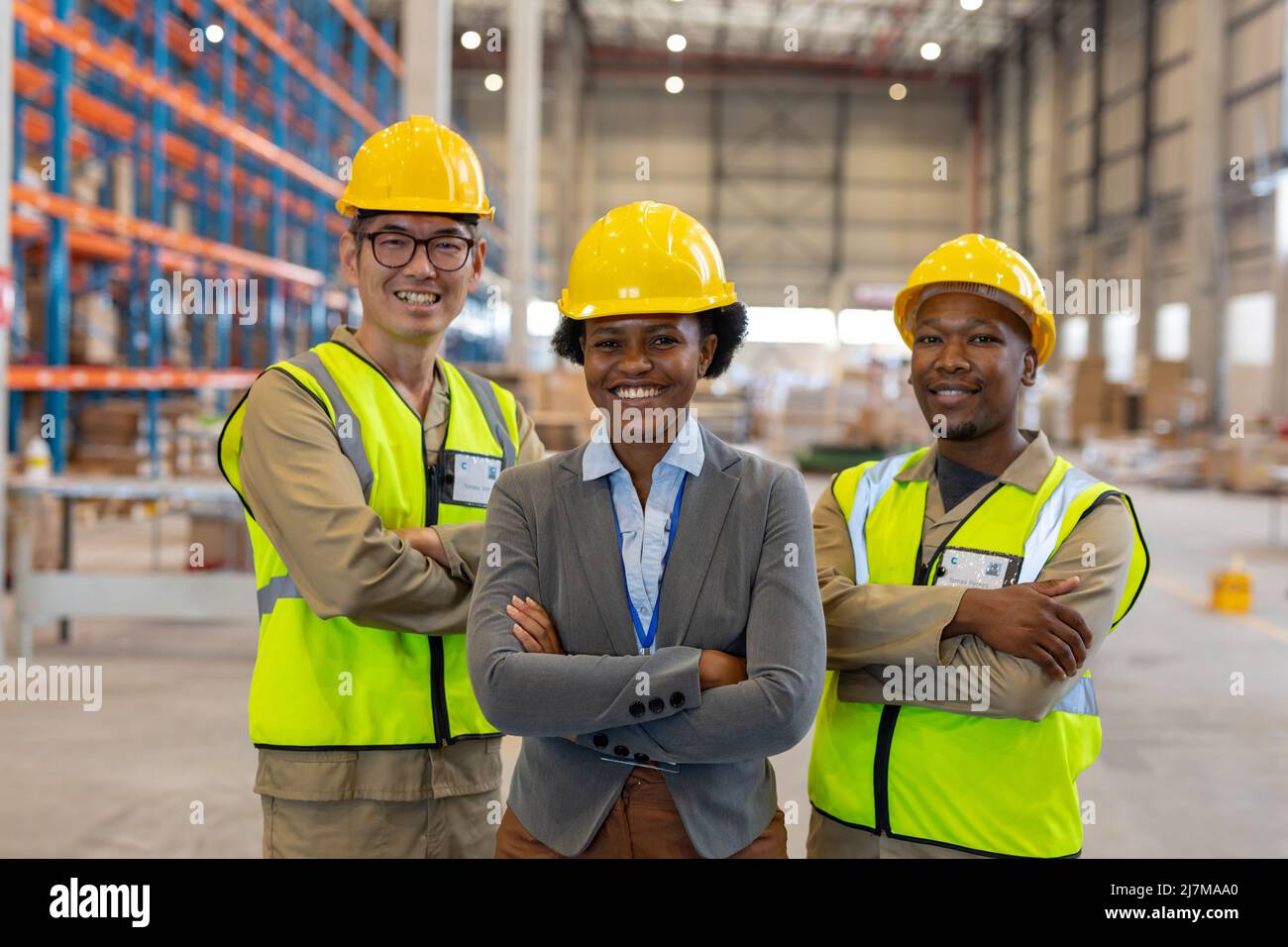 Smiling multiracial female and male coworkers wearing hardhats with ...