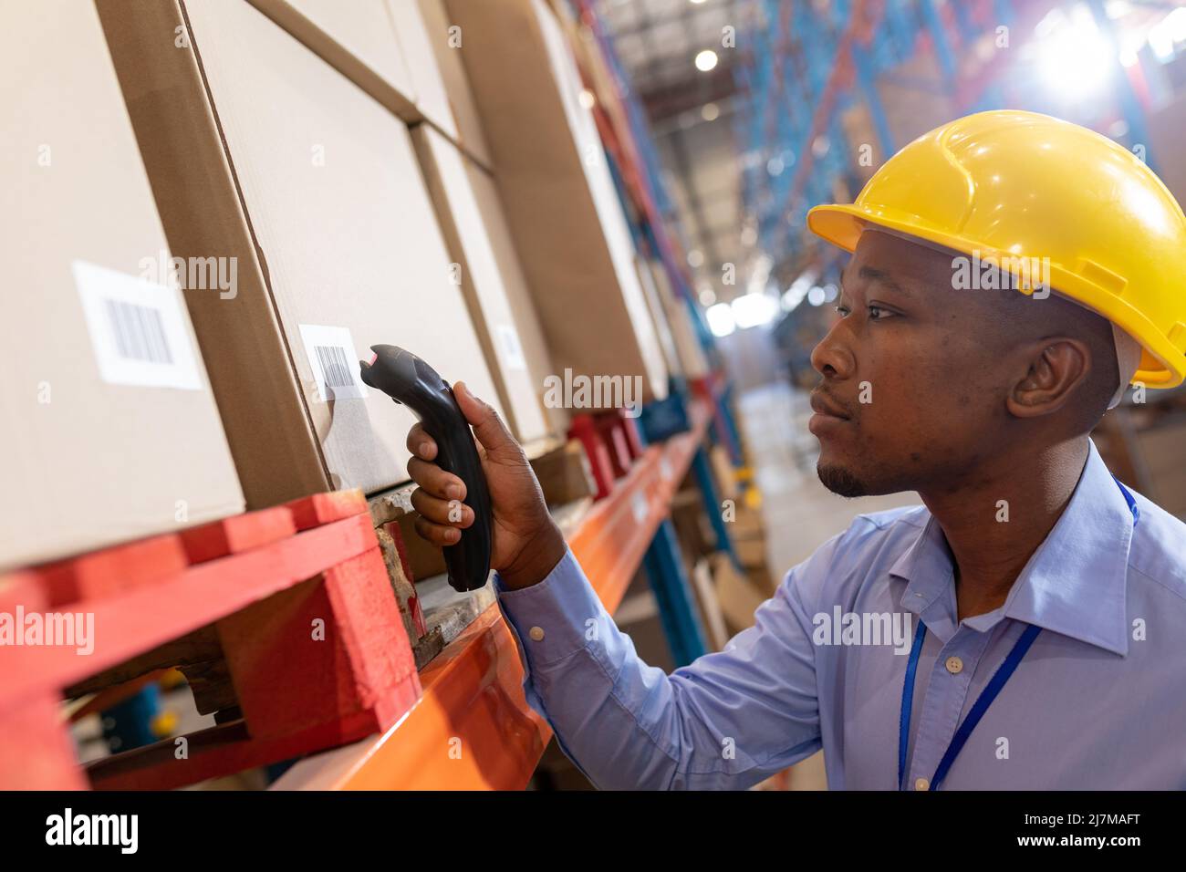 African american young male worker wearing hardhat scanning barcode on ...