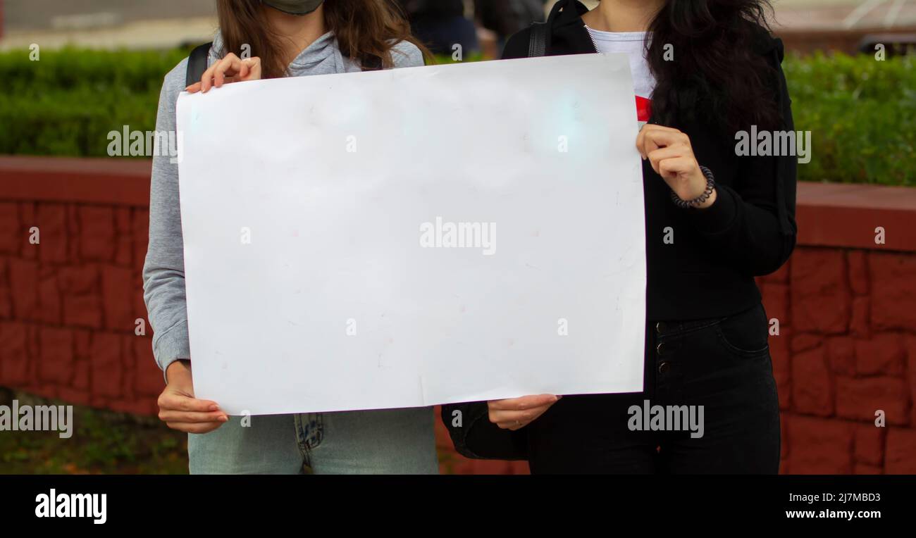 A blank sheet of paper or poster is held by two protesting girls Stock ...