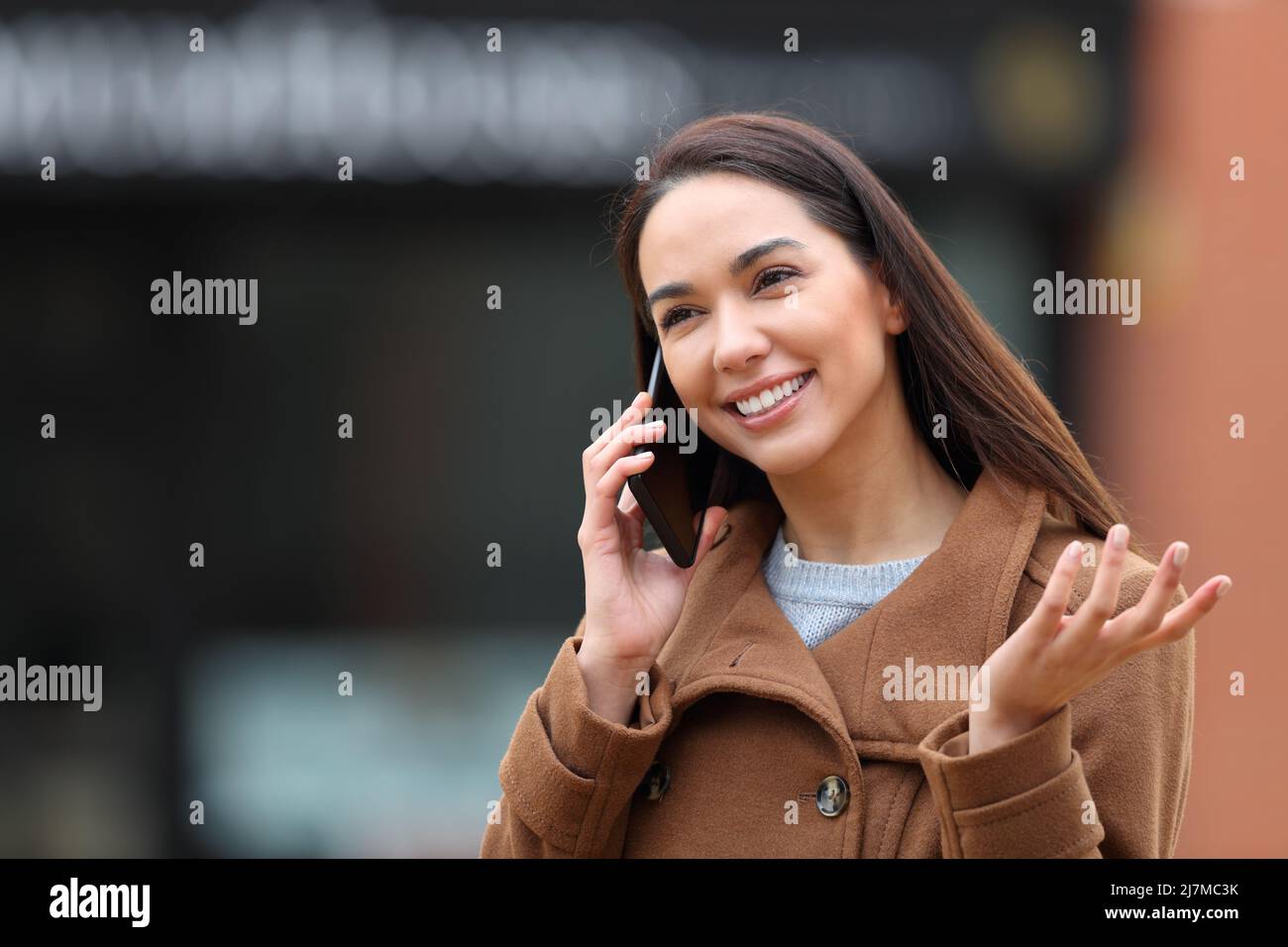 Happy woman in winter making a phone call in the street Stock Photo - Alamy