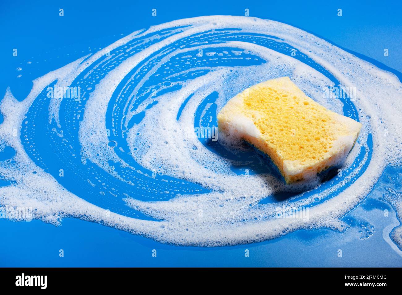 cleaning sponge wiping foam soap suds on blue background, household ...