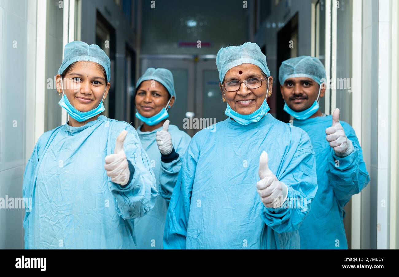 smiling group of surgeons showing thumbs up while at hosiptal corridor ...