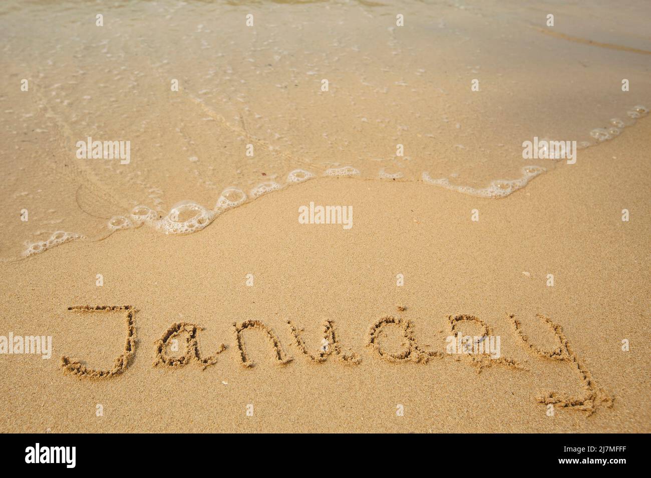 January - drawing on the soft beach sand with a soft lapping wave Stock ...