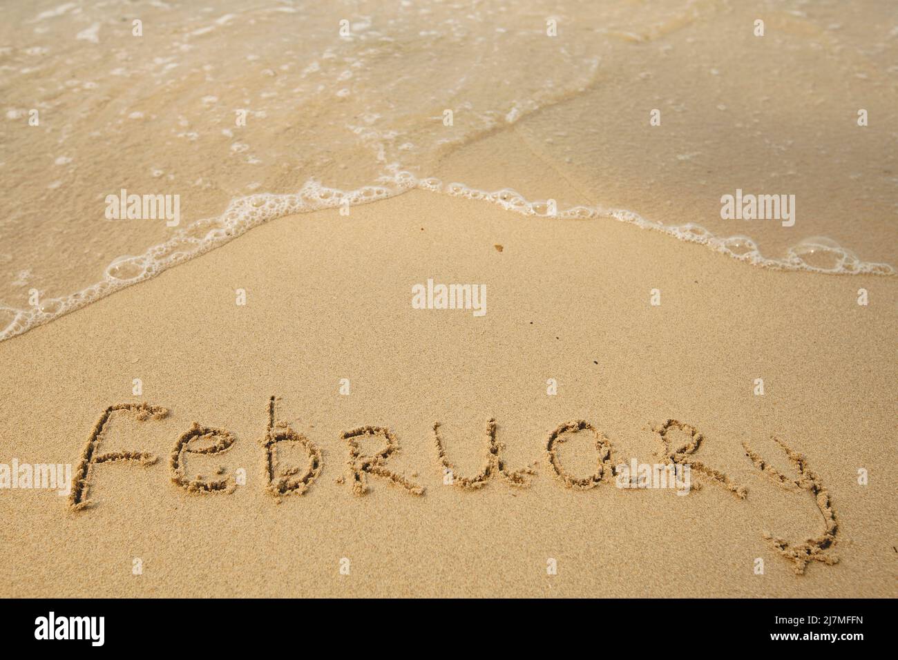 February - drawing on the soft beach sand with a soft lapping wave ...