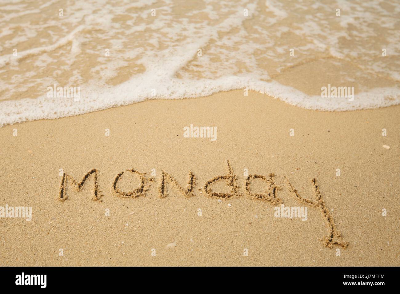 Monday - drawing on the soft beach sand with a soft lapping wave Stock ...