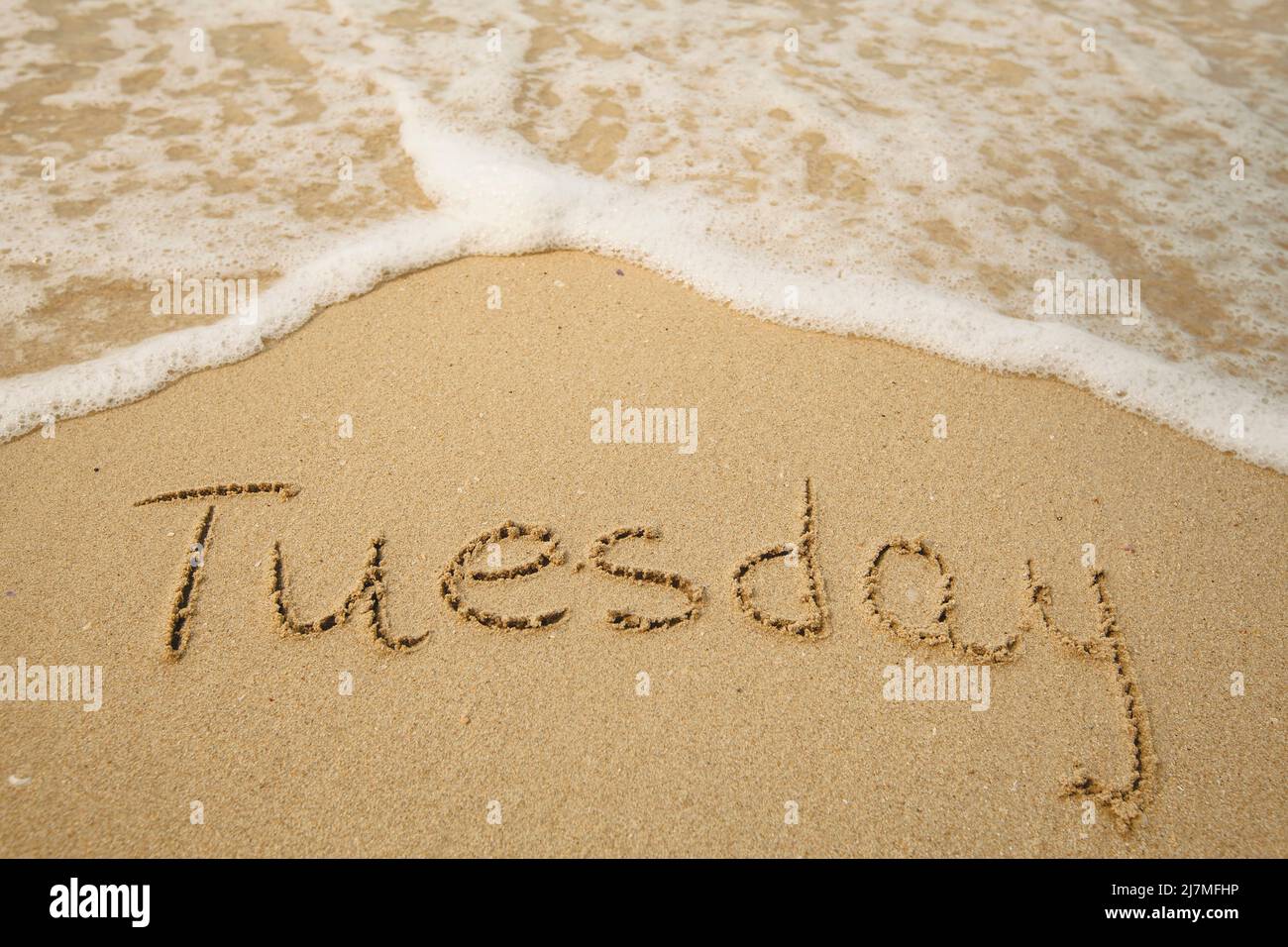 Tuesday - drawing on the soft beach sand with a soft lapping wave Stock ...