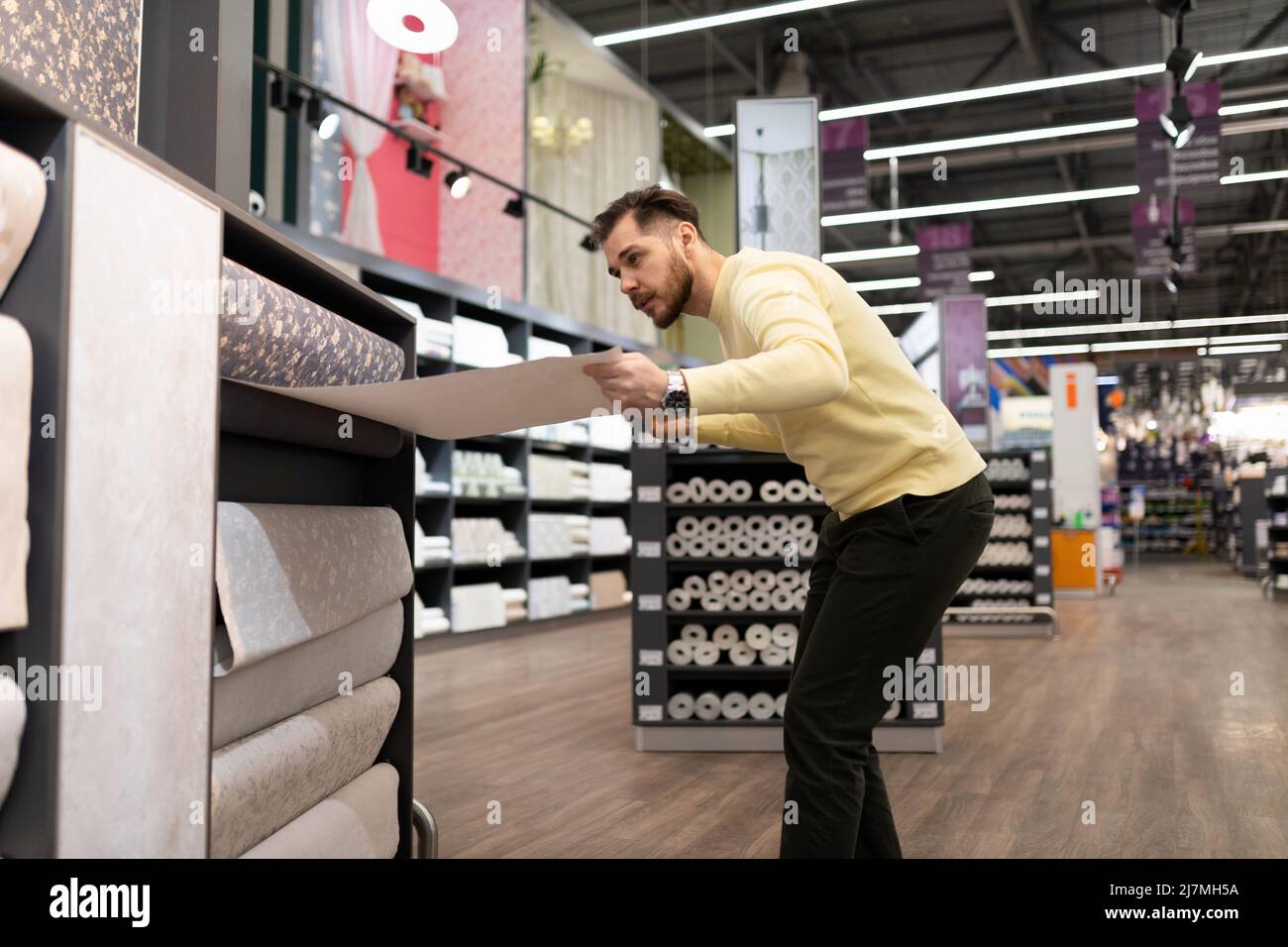a man in a hardware store chooses finishing materials for walls Stock ...