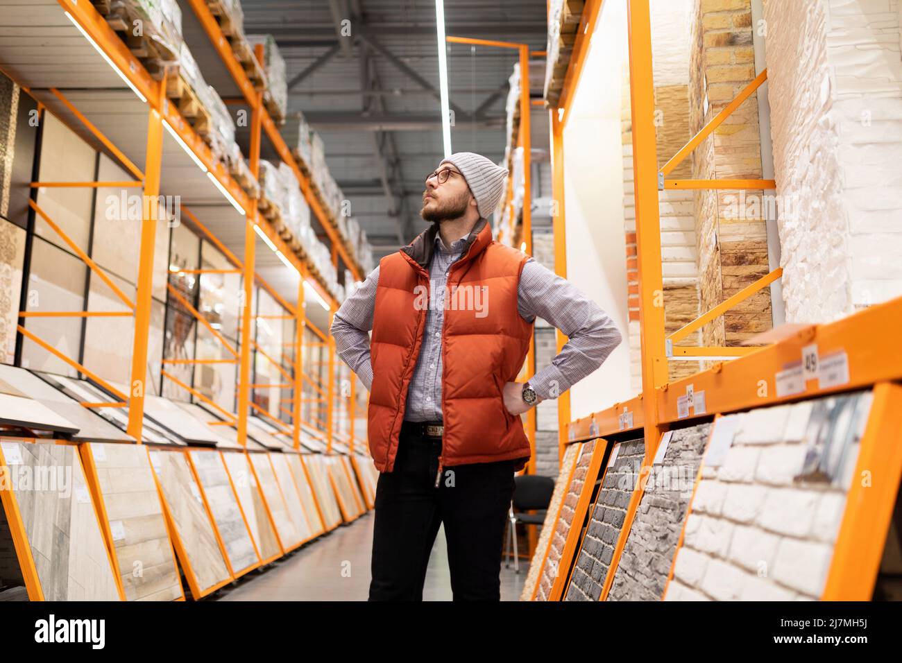 a buyer in a store of finishing materials examines shelves with ...