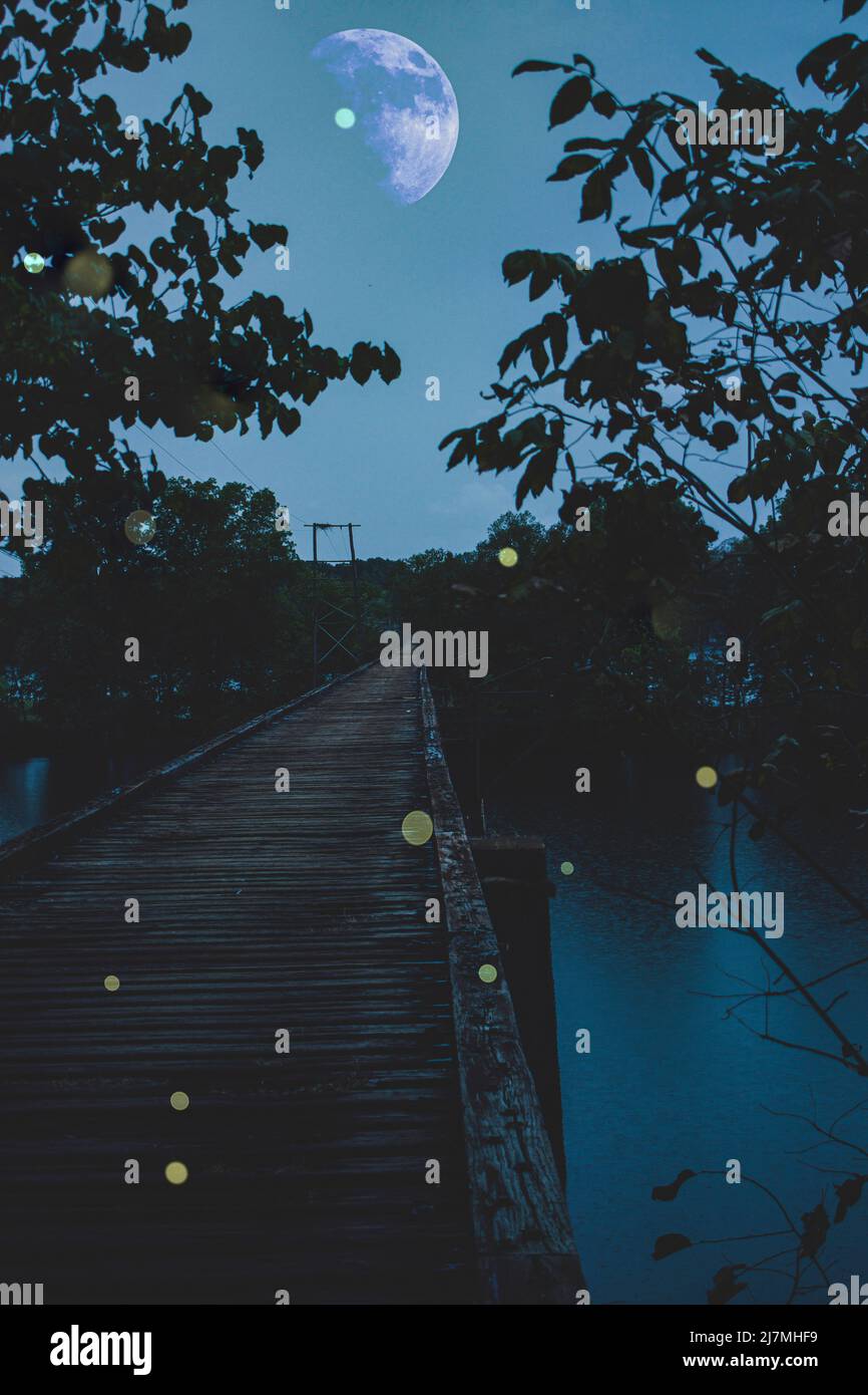 Old train bridge over water, with trees lining the way, with the moon ...