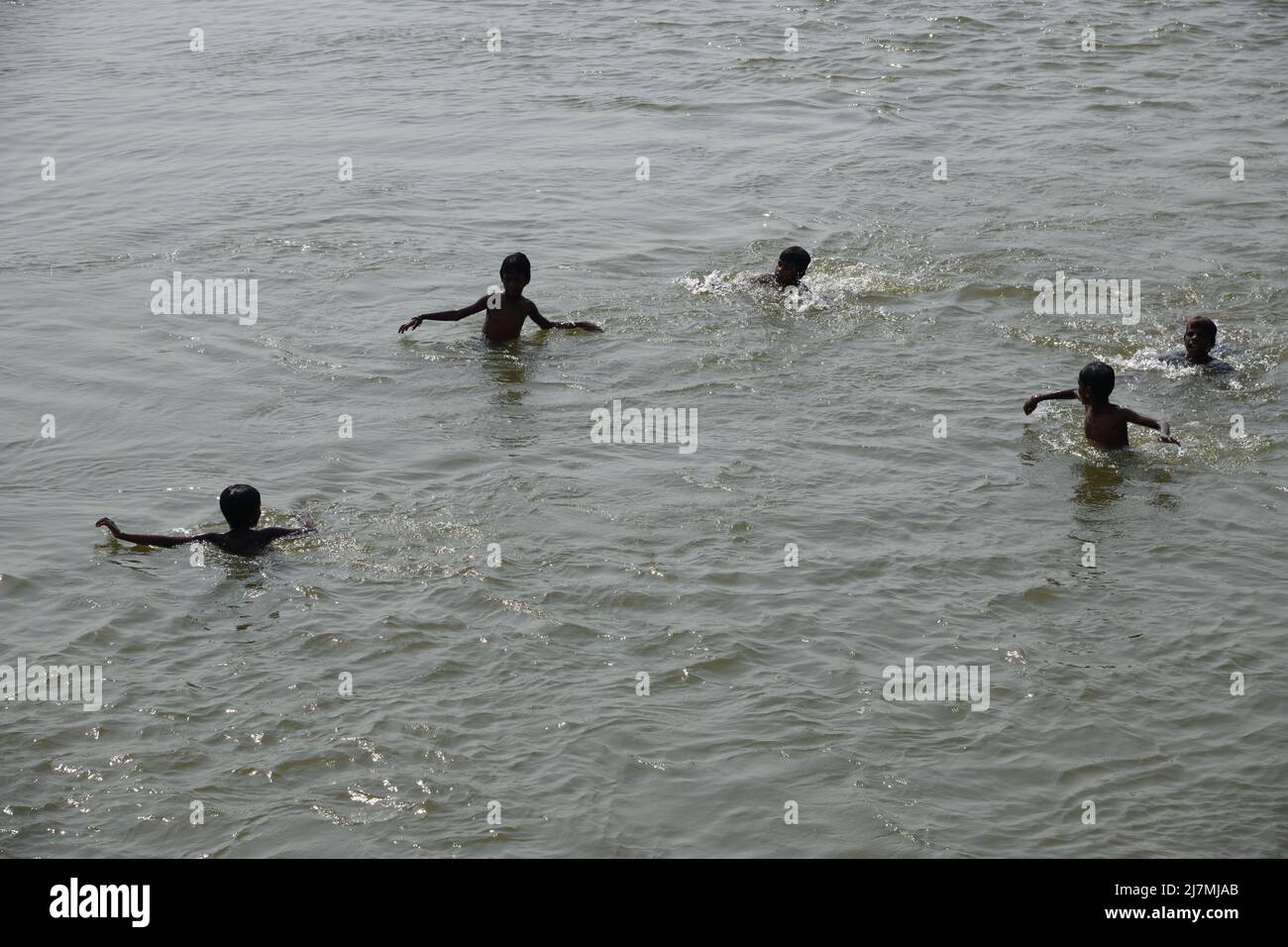 Local boys enjoying to play knee-deep water in the shallow riverbed in ...