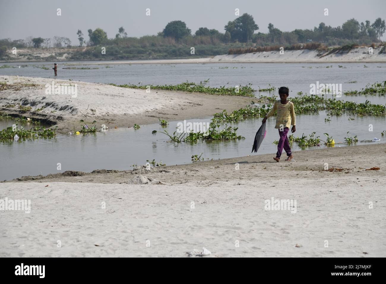 A boy holds kites crossing in the riverbed of the holy Ganges in the ...