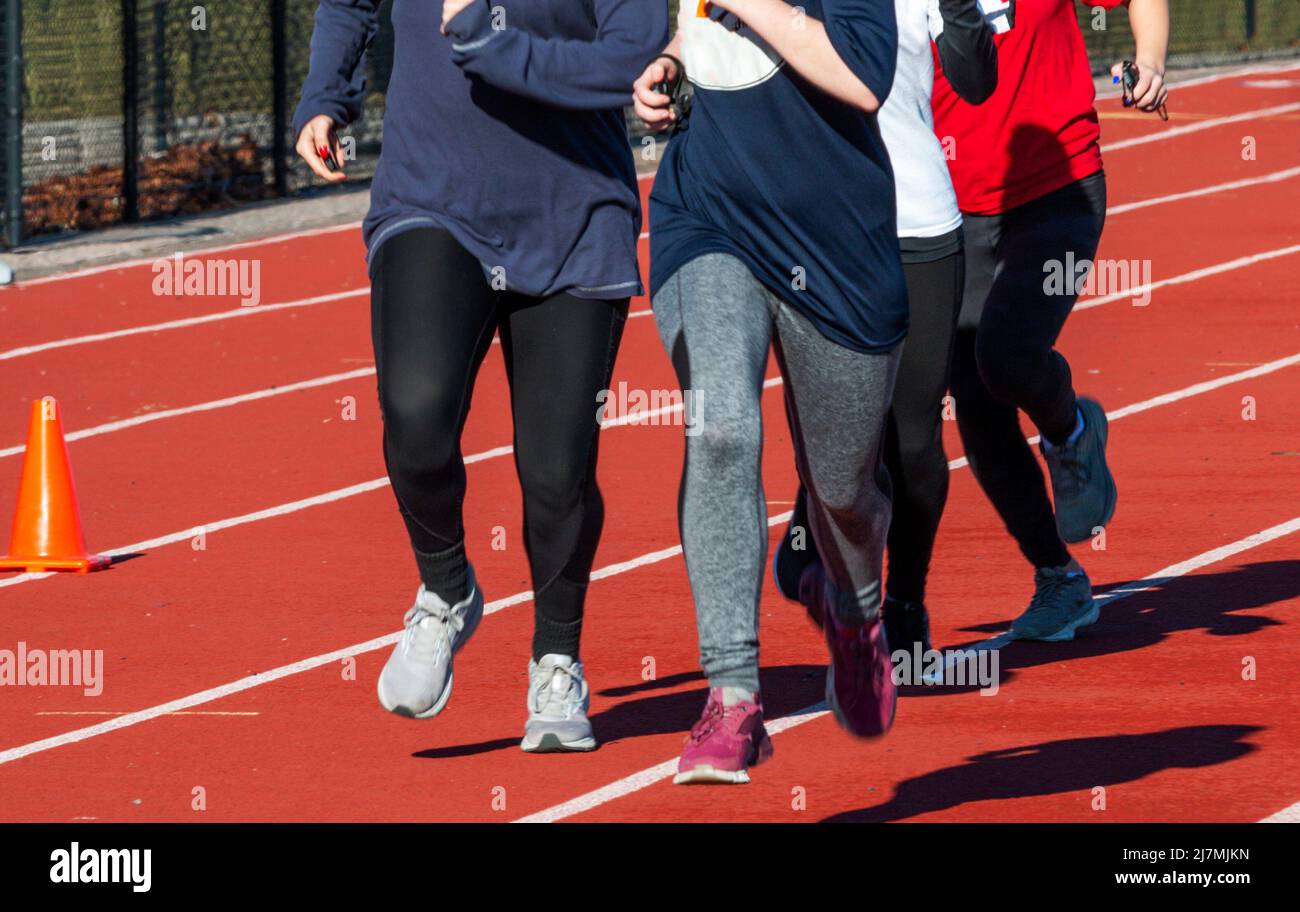 High school girls running in a group on a red track during track and ...