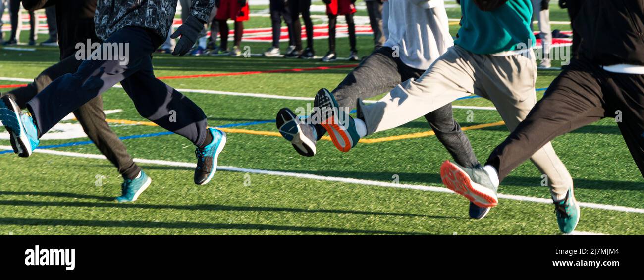 High school athletes performing running drills on a turf field on a ...