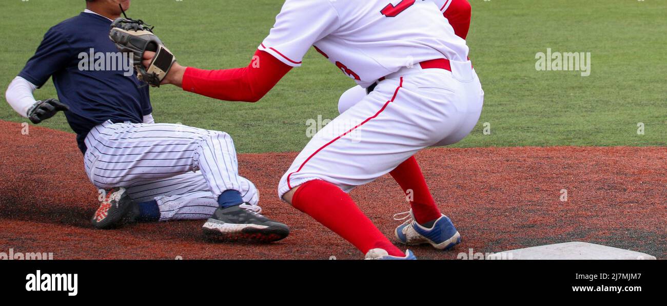 Third baseman applying the tag on an incoming runner who is sliding ...