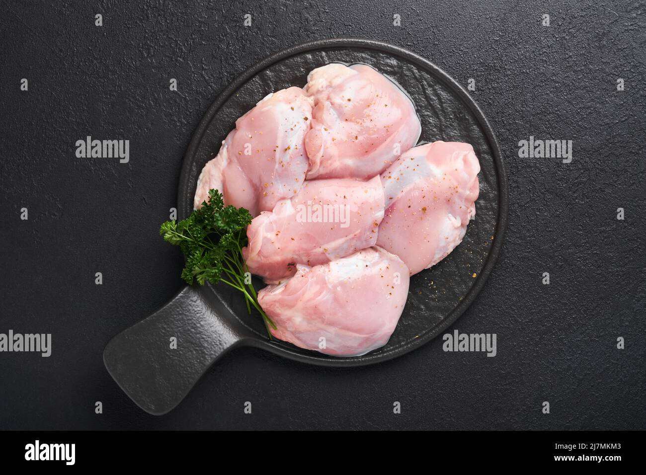 Raw chicken thigh fillet without skin with herbs and spices on black ...