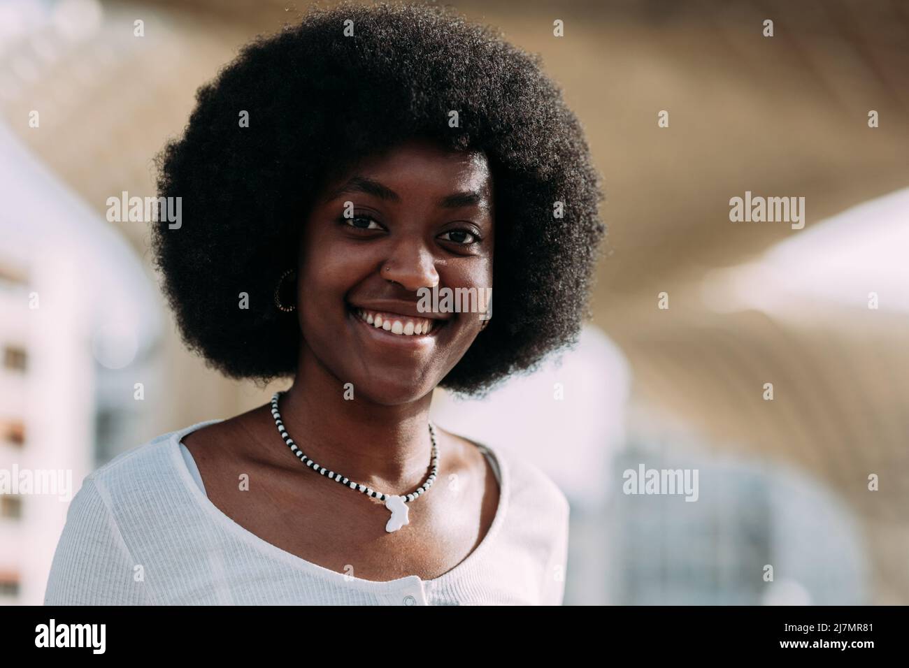 Portrait of a smiling young black woman with afro hairstyle on a sunny ...