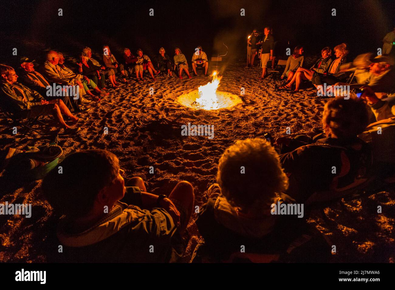People sitting camp fire illuminated hi-res stock photography and ...
