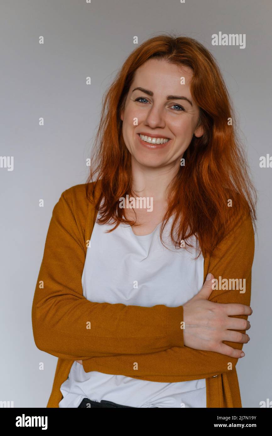 Happy Middle Aged Ginger Haired Woman In Her 40s Over White Wall