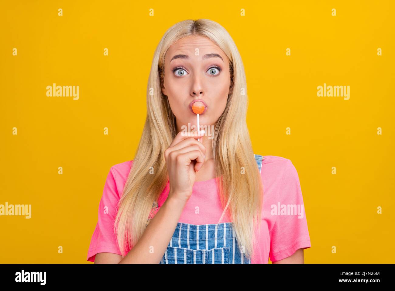 Portrait of attractive funny girly blond girl licking candy staring ...