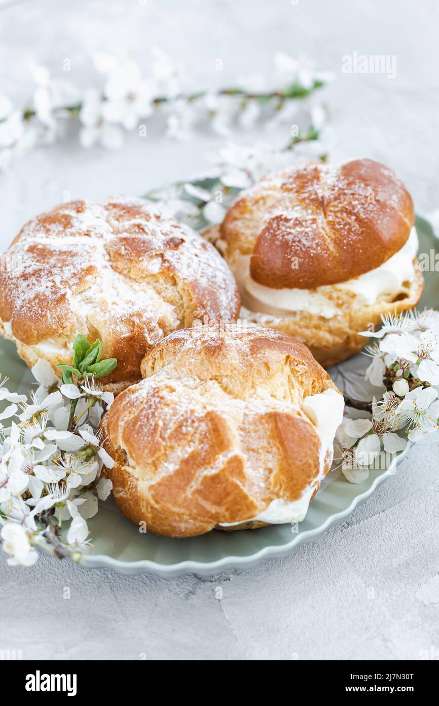 Choux Buns with whipped cream and sugar powder on top on plate. Gray ...