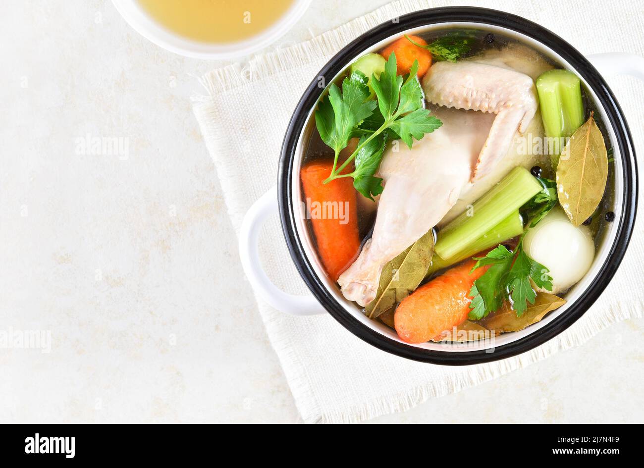 Chicken broth with vegetables and spices on light stone background with ...