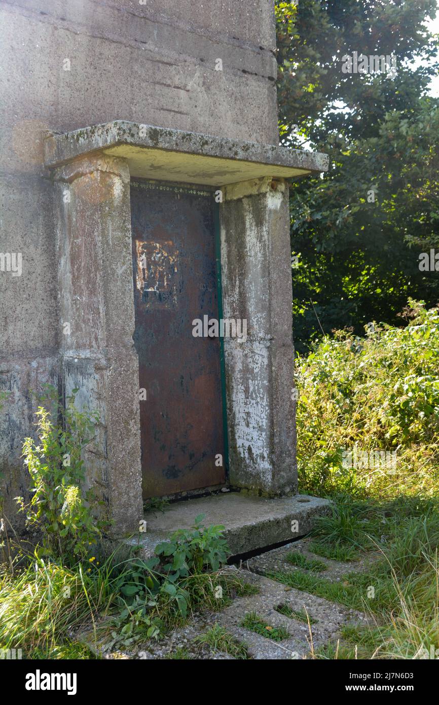 Lower part of an old border watchtower with a rusted entrance door on a ...