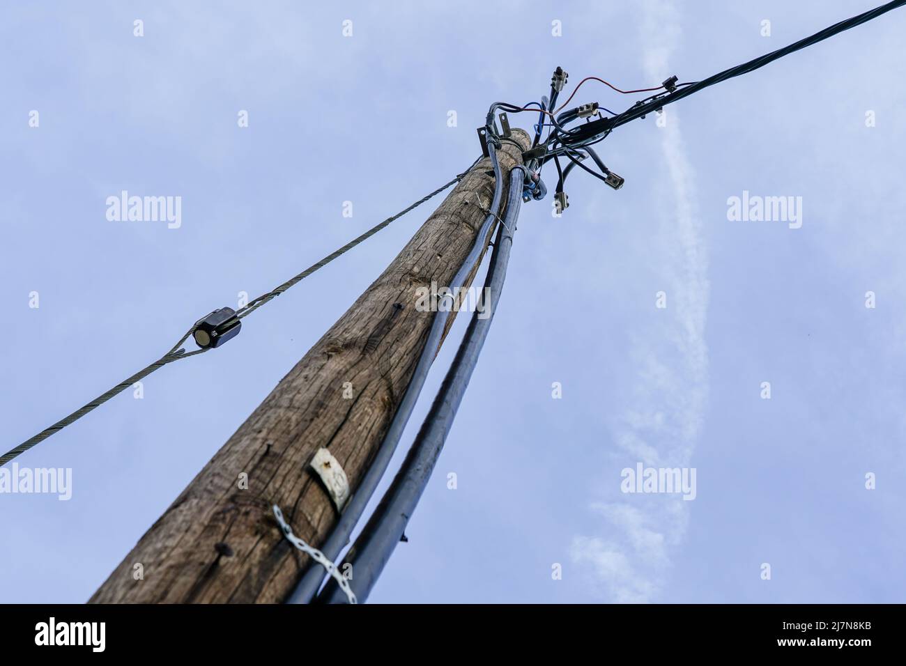 wooden electric pole with attached wires and cables on a blue sky ...