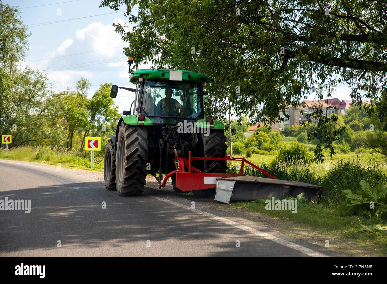 Big modern industrial tractor machine cutting green grass with mowing ...