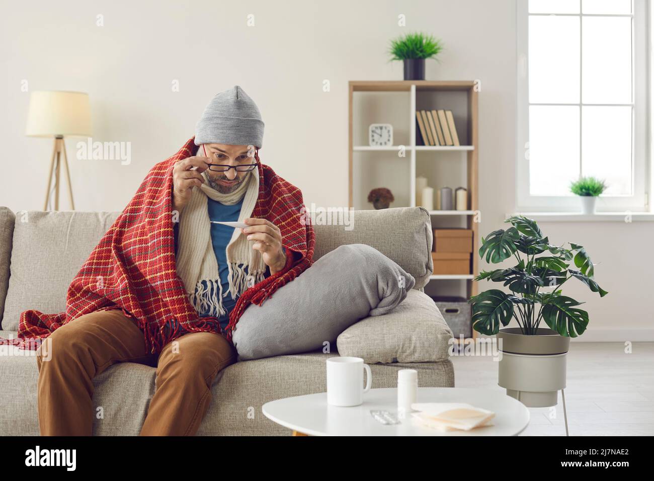 Man who has cold or flu takes his temperature and looks at thermometer ... Man who has cold or flu takes his temperature and looks at thermometer ...