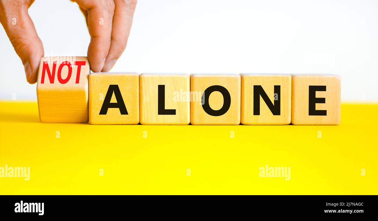 You are not alone symbol. Businessman turns wooden cubes and changes ...