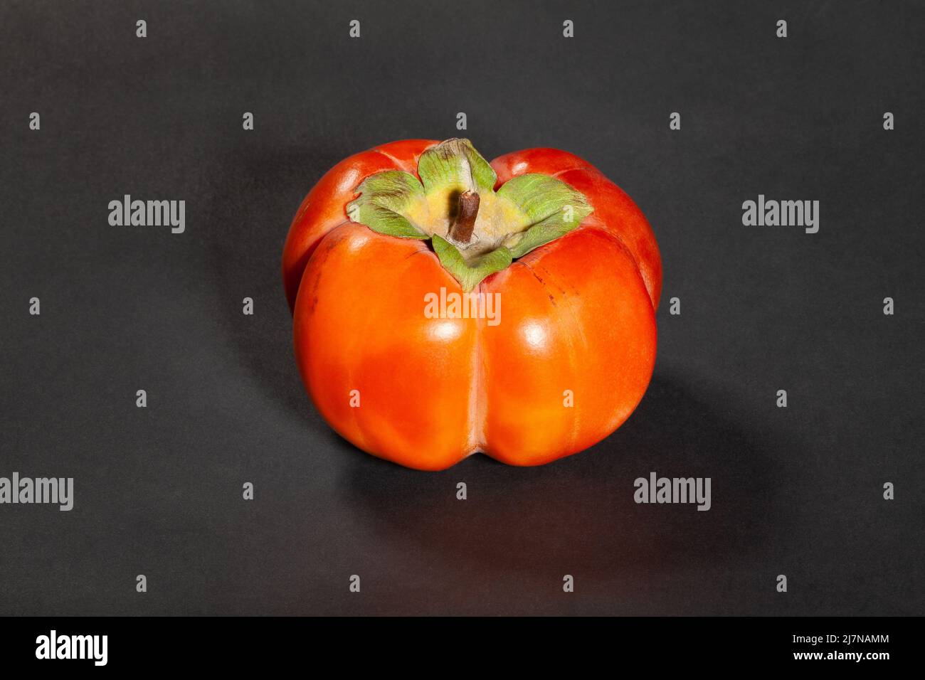 one persimmon on black background Stock Photo - Alamy