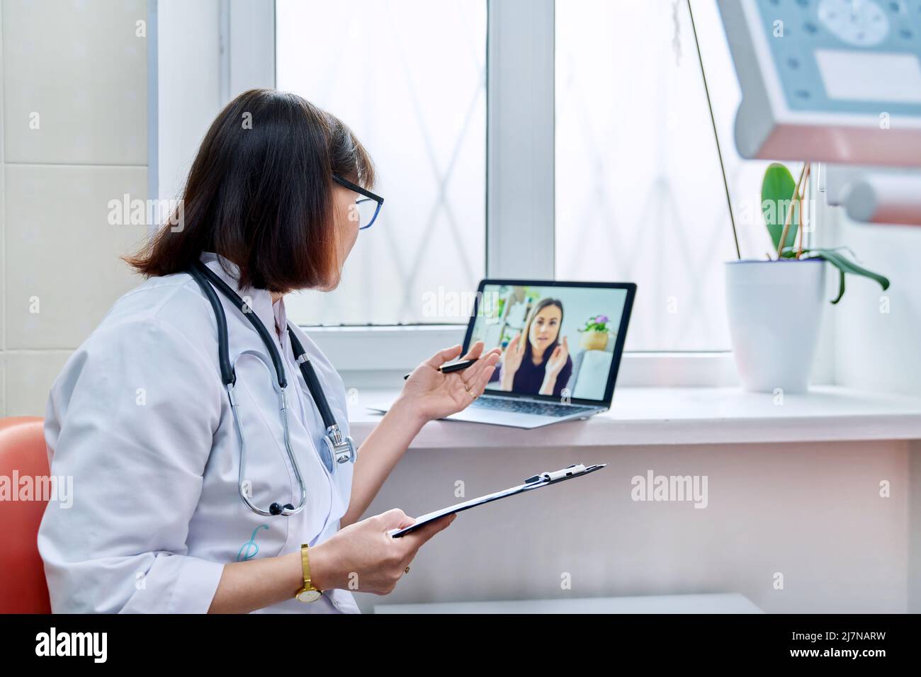General practitioner doctor talking on videoconference with female ...