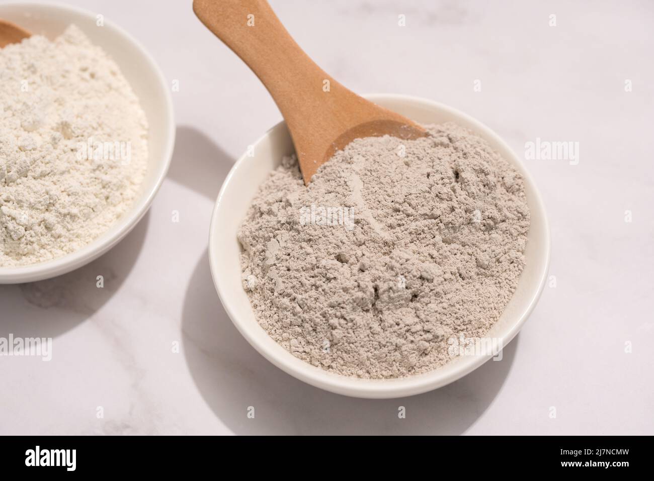 Closeup view of gray and white cosmetic clay on white marble table ...