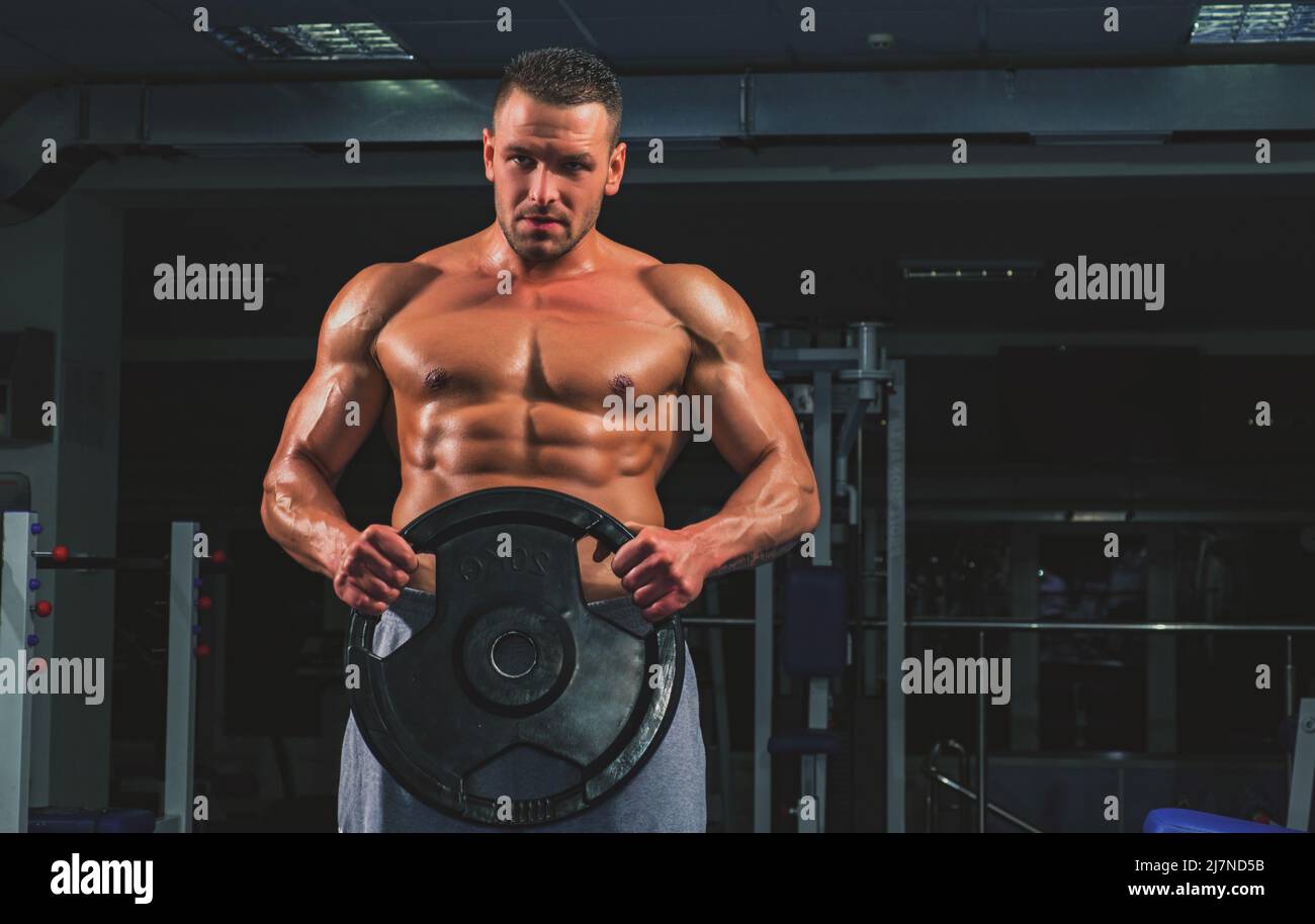 Powerlifter with weight disk in sport gym. Bodybuilder with heavy disk ...