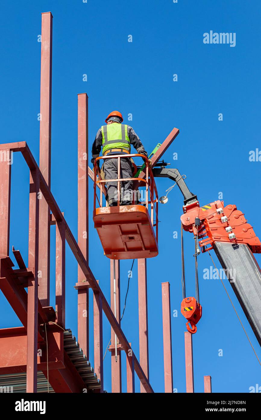 Male builders work at height in a lifting cradle, creating the iron ...