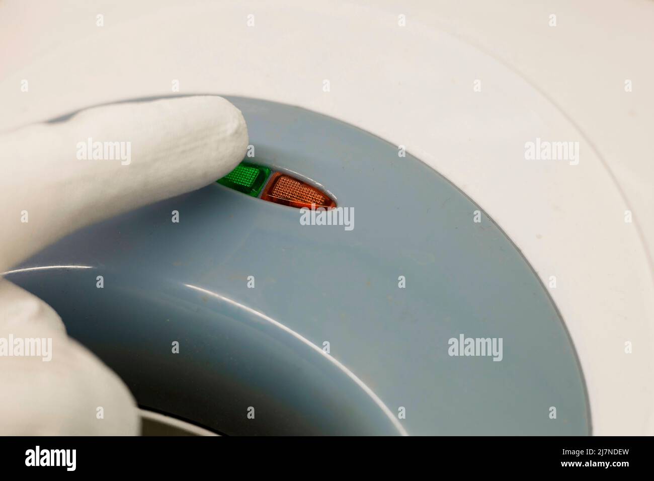 The finger pressing the red stop button starts the device. Start, stop ...