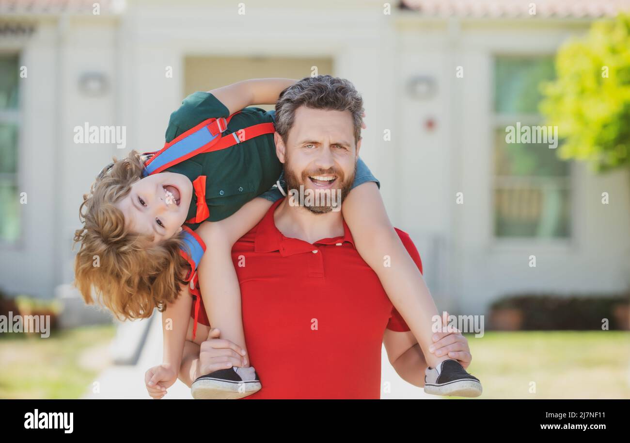 Father giving son piggyback ride after school study. Parent and pupil ...