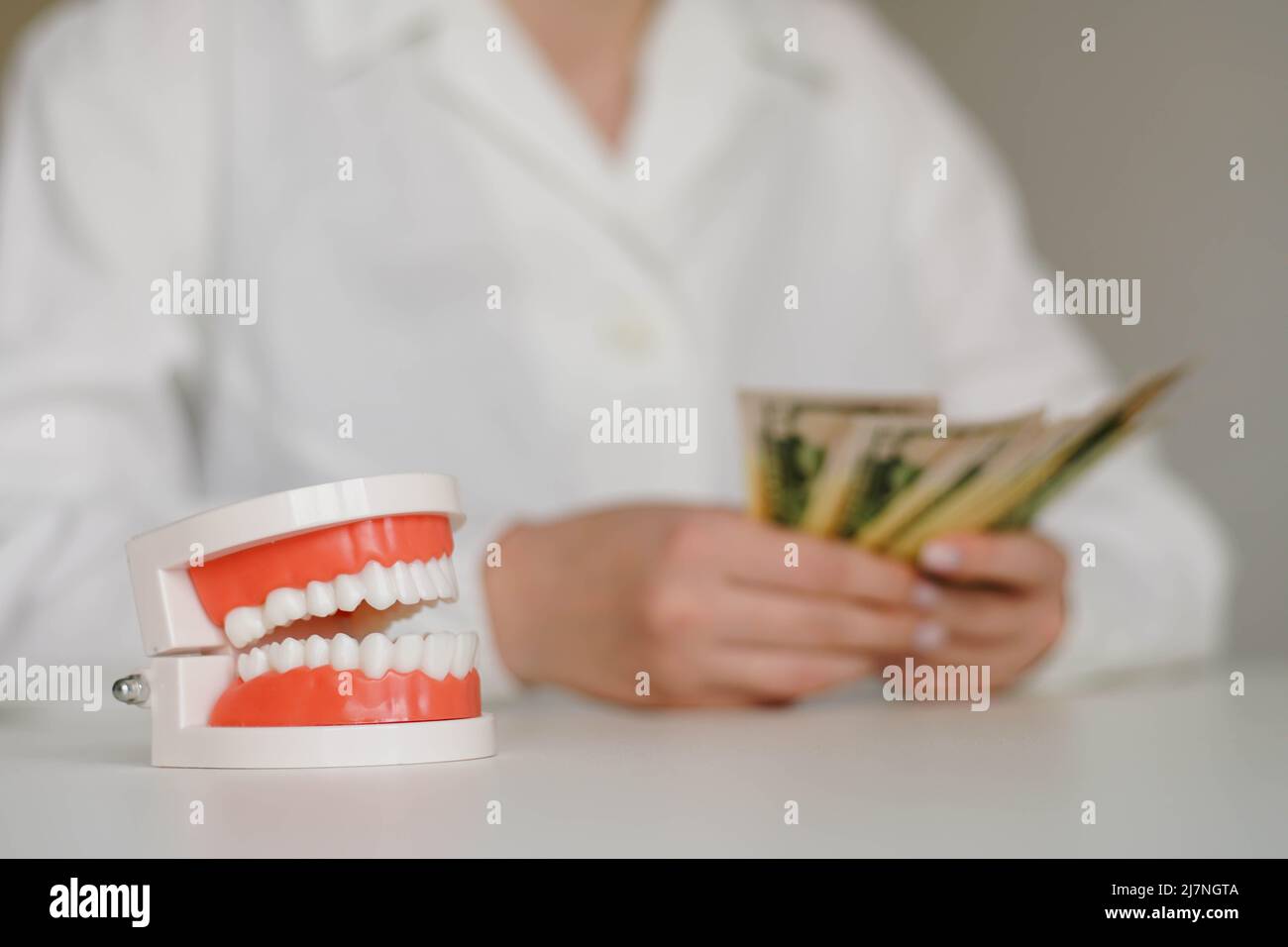 Dental artificial jaw. Woman dentist counting money on the background ...