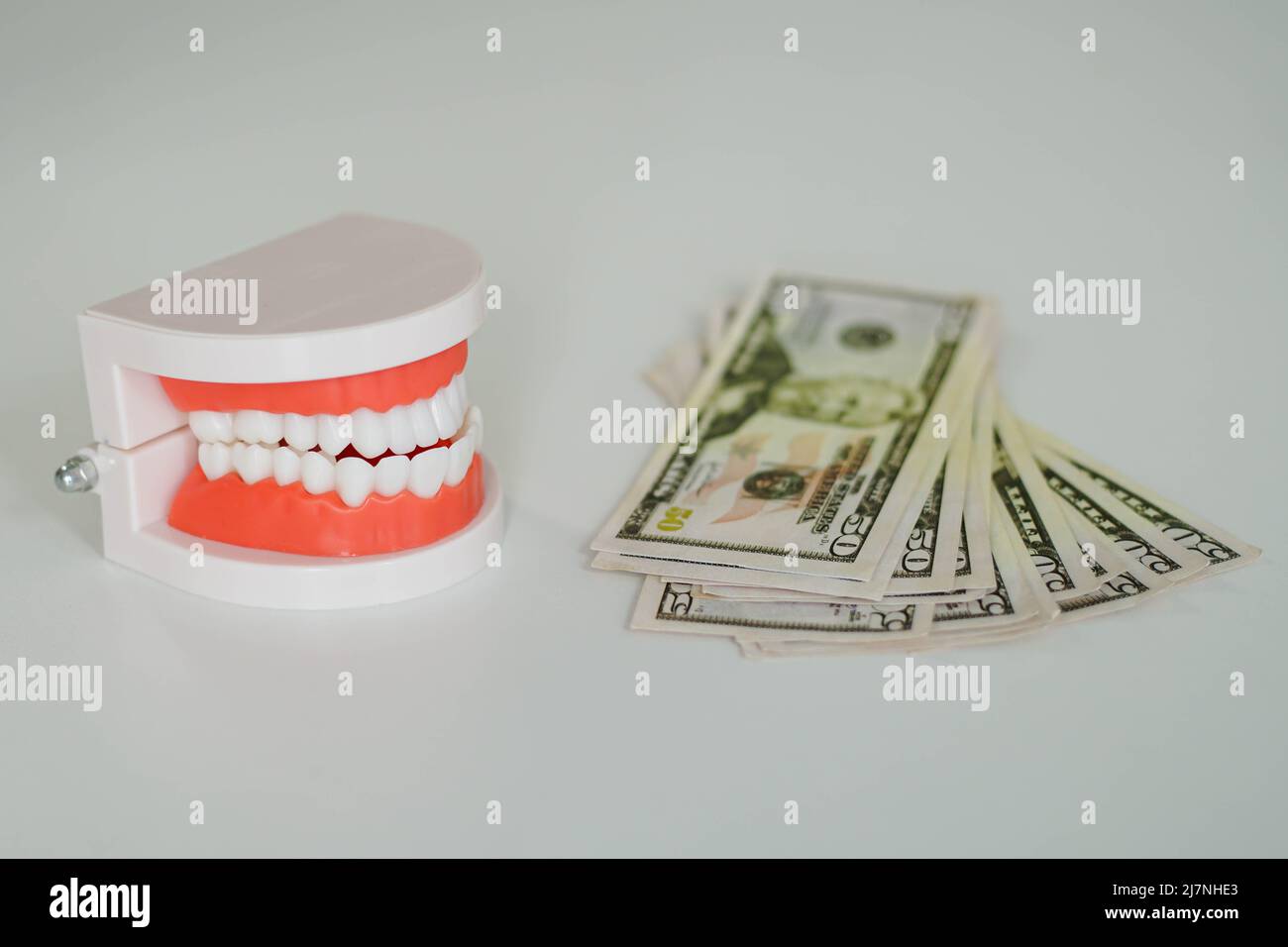Dental artificial jaw with pile of dollar banknotes. Expensive dental ...