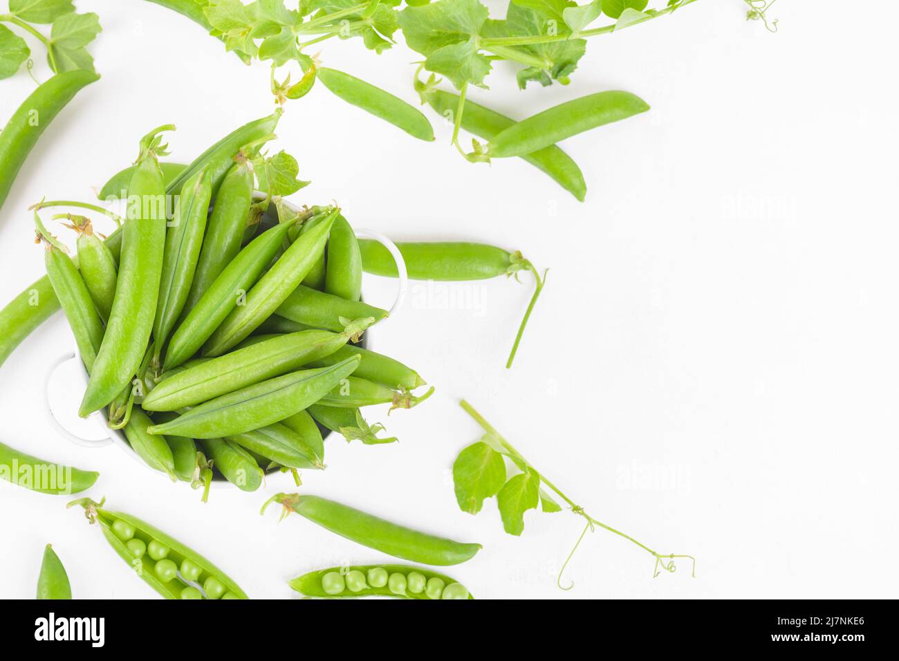 Fresh organic raw green peas peas pods in a bowl and plants leaves on ...