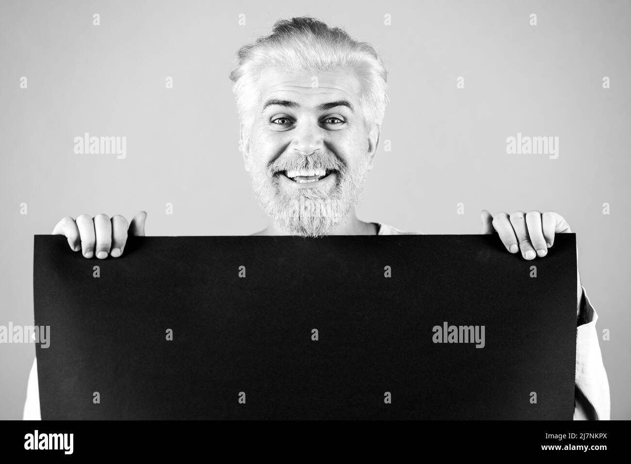 Happy Man holding empty sheet of a black paper. Colorful studio ...