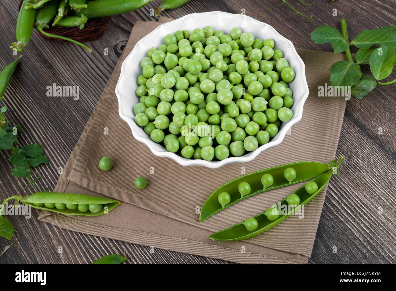 Fresh organic raw green peas in a bowl with peas plants leaves on dark ...