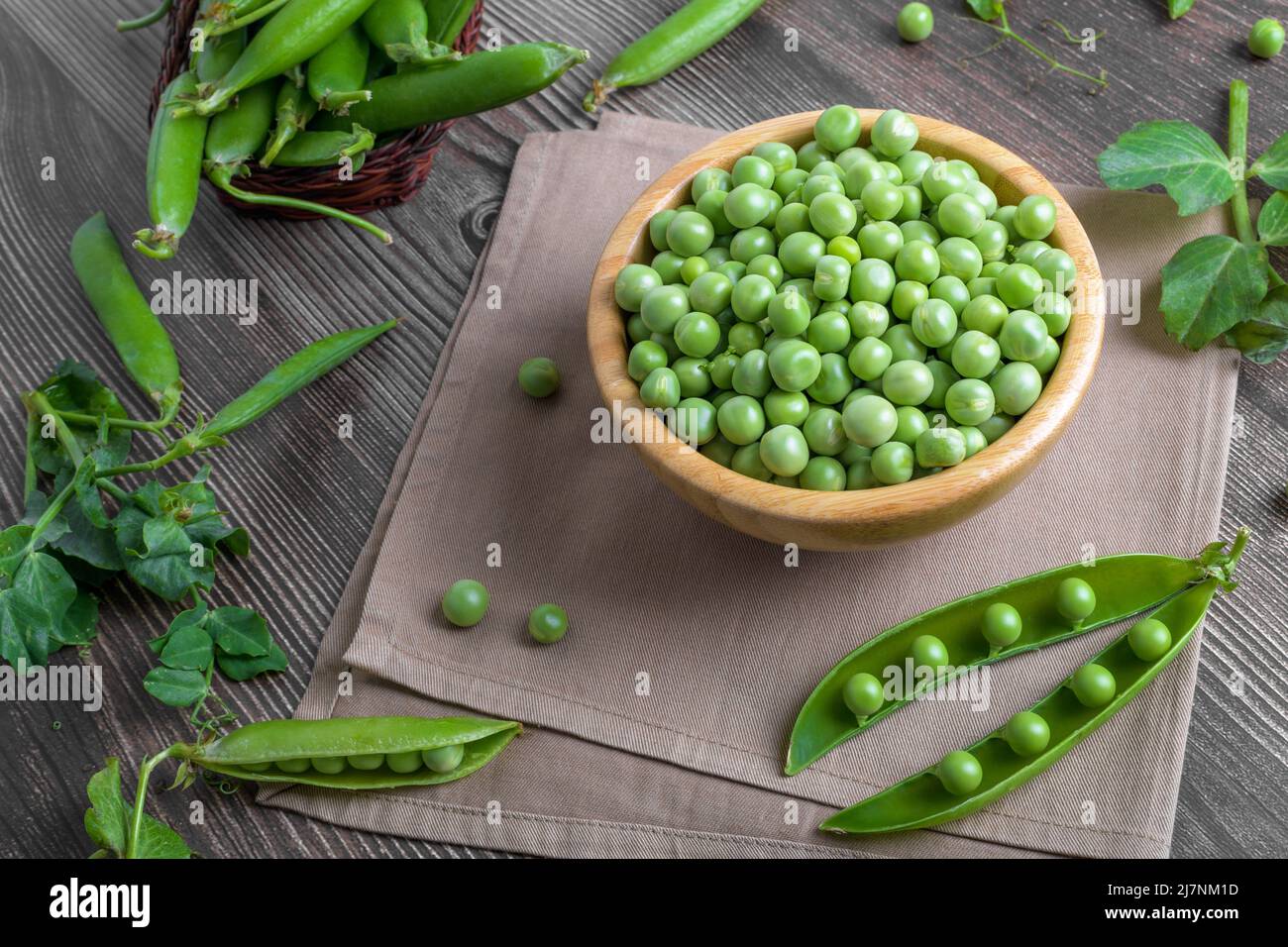 Fresh organic raw green peas in a bowl with peas plants leaves on dark ...