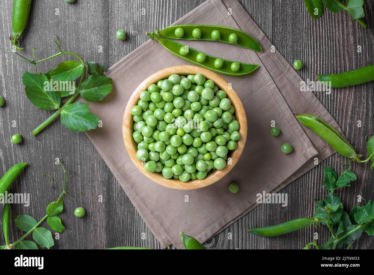 Fresh organic raw green peas in a bowl with peas plants leaves on dark ...
