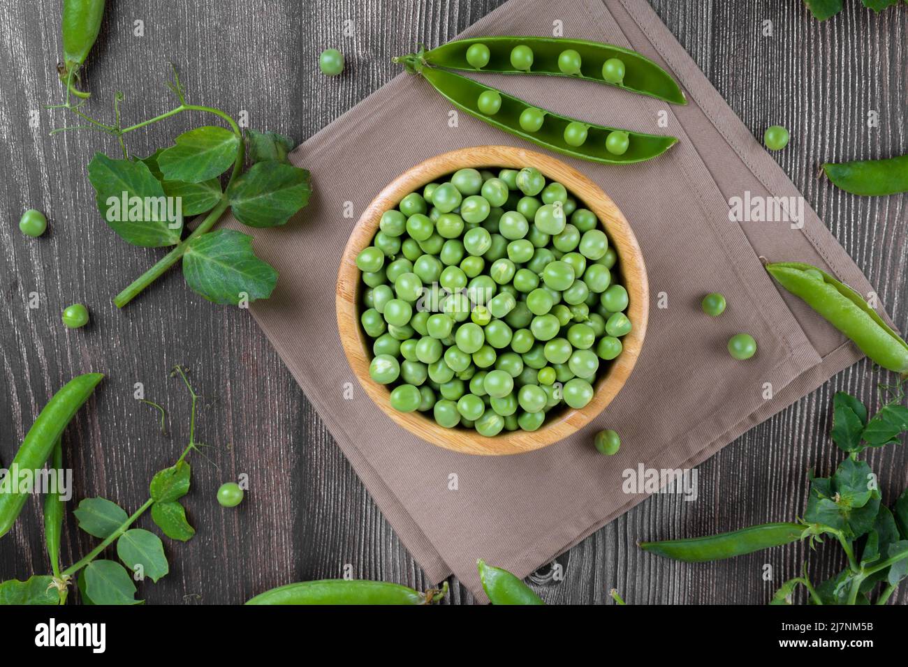 Fresh organic raw green peas in a bowl with peas plants leaves on dark ...