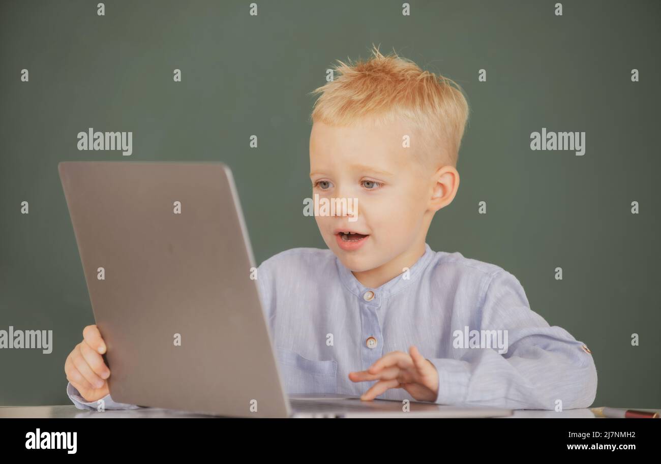 Little student boy using laptop computer in school class. Little funny ...