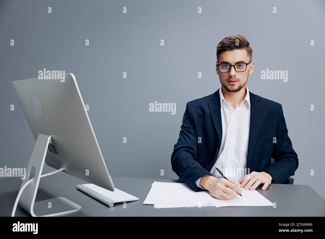 businessmen wearing glasses works in front of a computer Gray background Stock Photo - Alamy