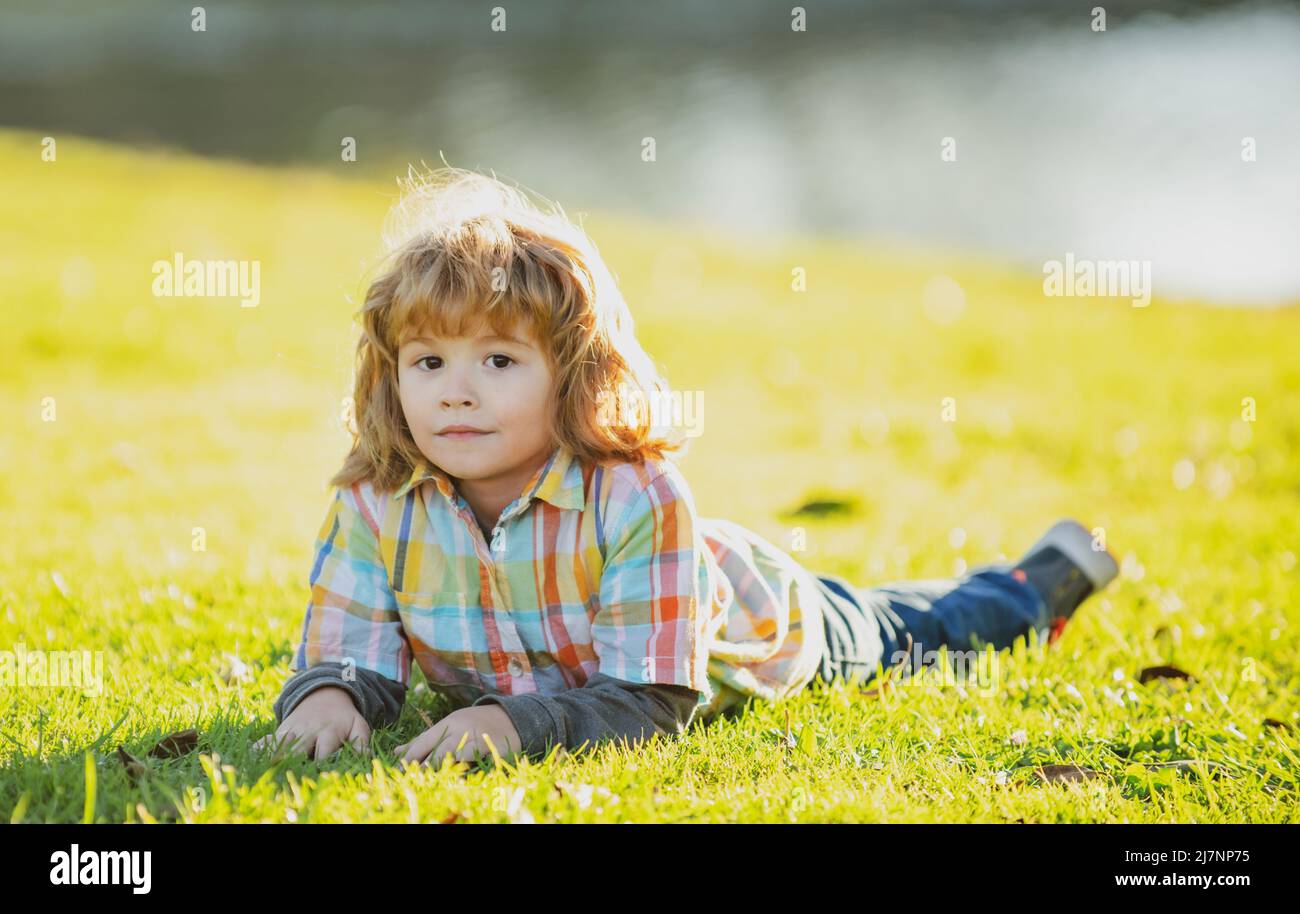 Kids outdoor. Children in park. Spring Boy lying on grass. Summer walk ...