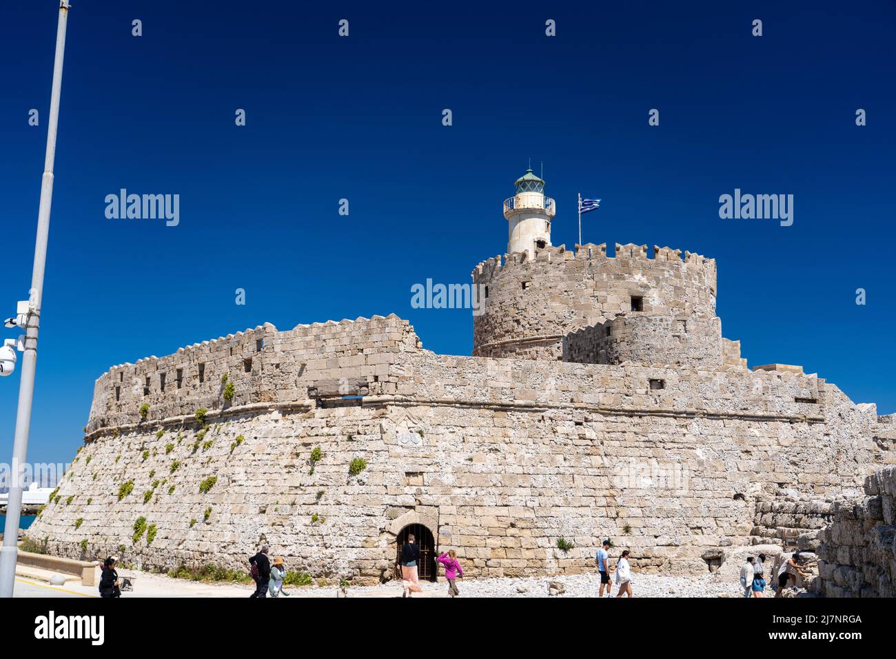 Saint Nicholas Fortress in Mandraki Harbor in focus and Seaside chair ...