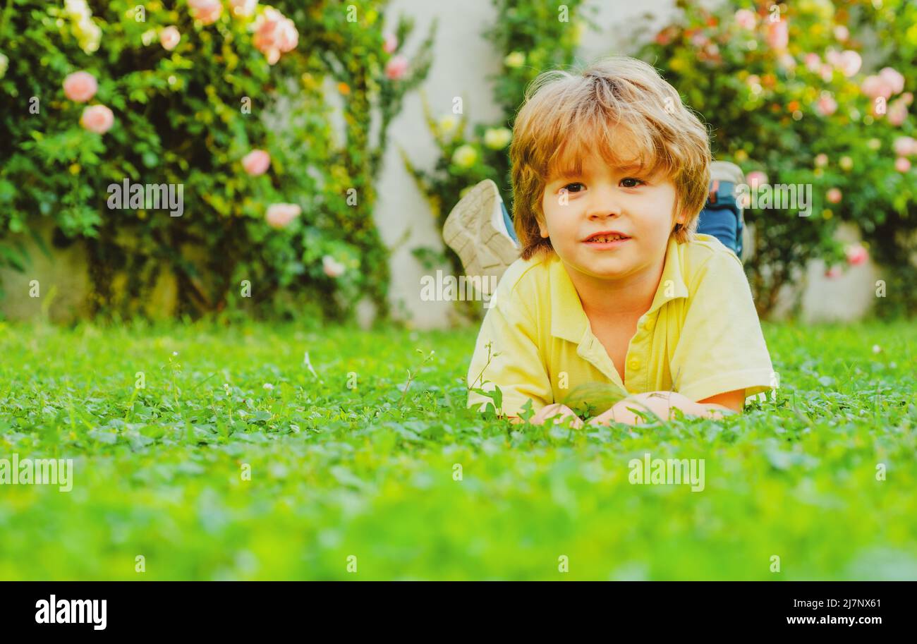 Kid in park or garden outdoor. Spring child lying on grass. Summer boy ...